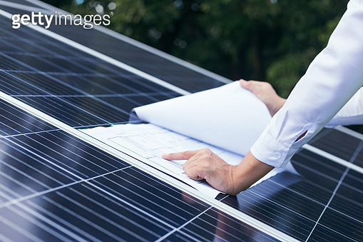 Engineer open blueprint of solar farm project on solar cells panel ...
