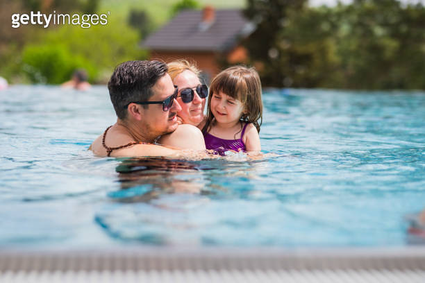 Parents hugging their young daughter in the swimming pool 이미지 ...