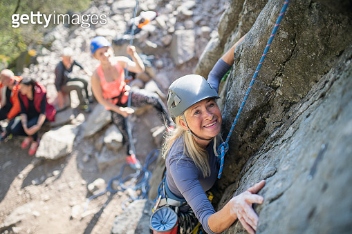 Group of seniors with instructor climbing rocks outdoors in nature ...