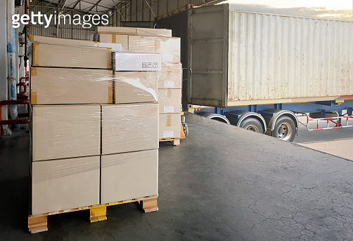 Stack of cardboard on pallet rack. Cargo trailer truck parked loading ...
