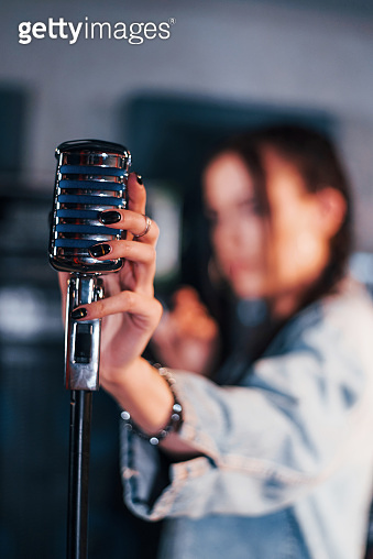 Close up view of microphone. Young beautiful female performer ...