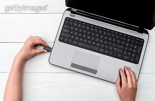 Hand inserting USB flash drive into laptop computer on white background ...