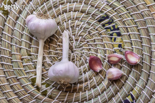 organic dried garlic bulbs and separated garlic cloves in woven basket ...