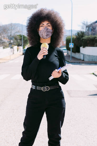 Female television reporter journalist with afro hair, wearing a leopard ...