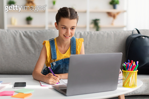 Cheerful girl sitting at desk, using laptop, drawing in copybook 이미지 ...