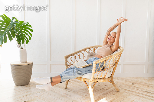 Gorgeous lady stretching in wicker armchair while reading book ...