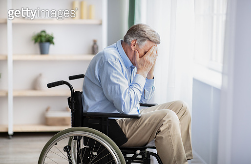 Unhappy and lonely senior handicapped man in wheelchair crying at home ...