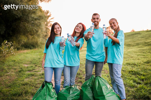 Young volunteers with garbage bags taking break while cleaning park ...