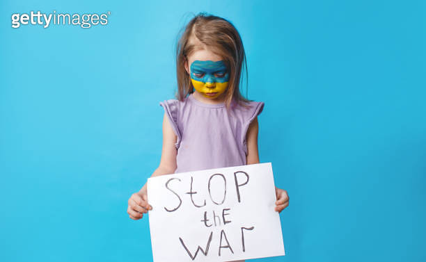 a sad girl with a split face in the colors of the Ukrainian flag holds ...