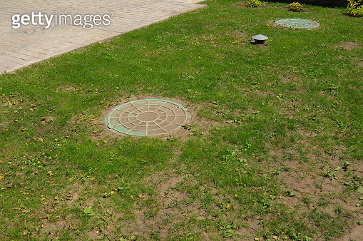 Two manhole covers on the green lawn of a septic tank system, sewer ...