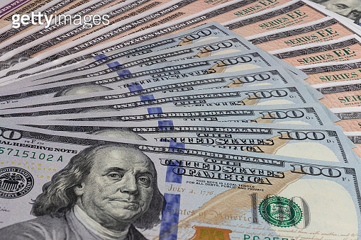 US Savings Bonds and 100 Dollar bills, representing investment choices ...