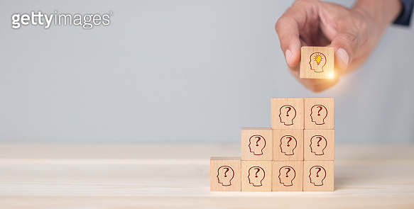 Hand business picked wooden cube block with head human symbol and light ...