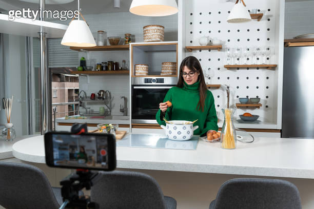 Young vlogger woman vlogging about cooking at her apartment domestic ...