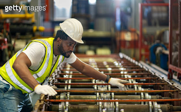 African American industrial worker is checking the setup value of metal ...