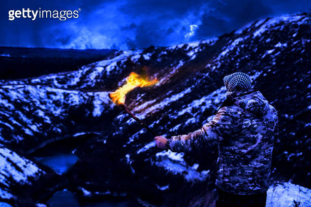 Soldier is holding torch with fire. Man in camouflage uniform and ...