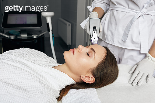 Pretty woman enjoying radiofrequency lifting procedure for her face and ...
