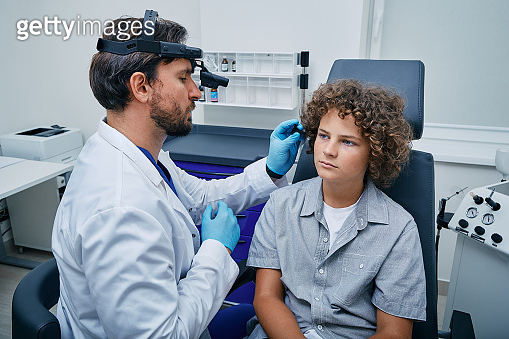 Ear check-up in child, otolaryngology. Curly boy patient during ear ...
