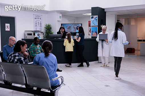 Front Desk Receptionist Talking With Young Girl Patient Registering For 