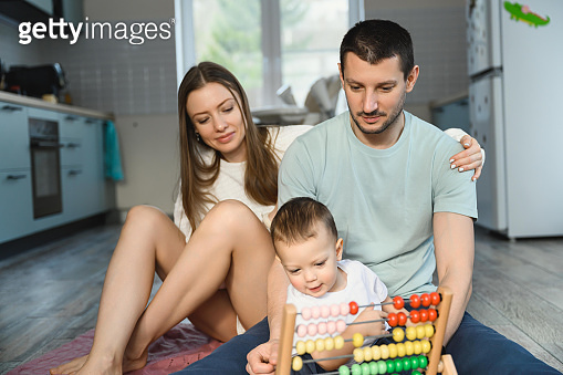 Father and mother teach the baby to count on the abacus. The child is ...