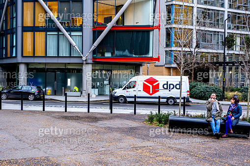 Two People Sitting Relaxing With DPD Courier Delivery Van In The ...