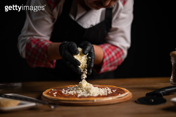 A male chef adding cheese to pizza 이미지 (1434541295) - 게티이미지뱅크