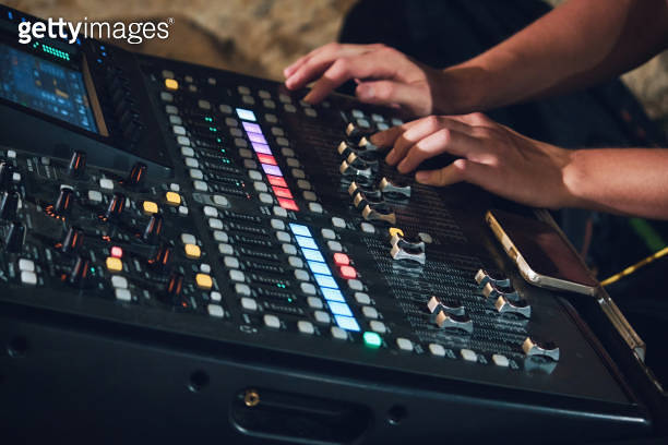 Shot of a multi-track sound mixer for live events with a man's hands on ...