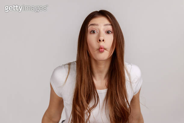 Woman with dark hair making fish face grimace with pout lips and ...