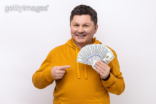 Rich man pointing at big fan of dollars banknotes with finger, rejoices ...