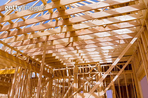 New house construction interior with wood roof trusses exposed framing ...
