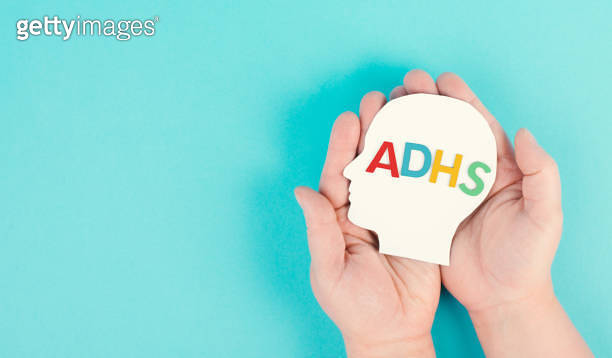 Hands holding a head with the german word ADHS which means attention ...