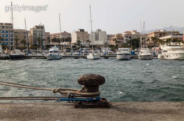 Mooring dolphin on port with boats and town in background. Roquetas del ...