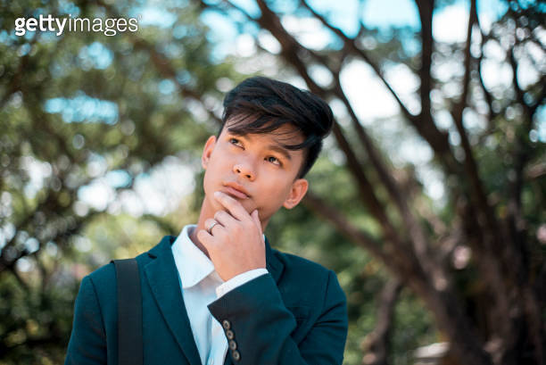 A young university student thinking and doubtful with finger on chin ...