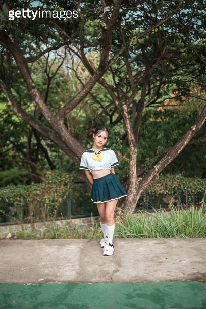 A cute and pretty asian student cosplayer in a cropped top, miniskirt ...