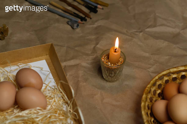 Candle with light. Rustic background. Tools for decorating Paschal eggs ...