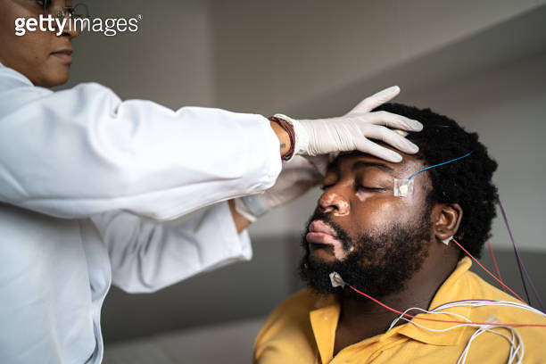 Doctor placing electrodes on patient's head for a polysomnography ...