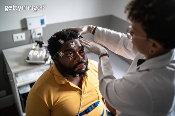 Doctor placing electrodes on patient's head for a polysomnography ...