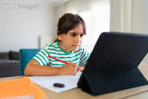 Child sitting alone at home and feeling stressed while doing her ...