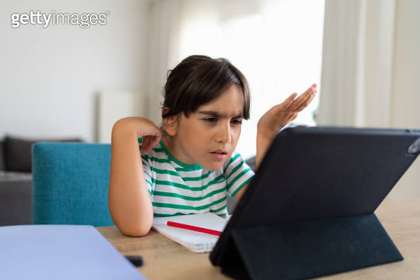 Child sitting alone at home and feeling stressed while doing her ...