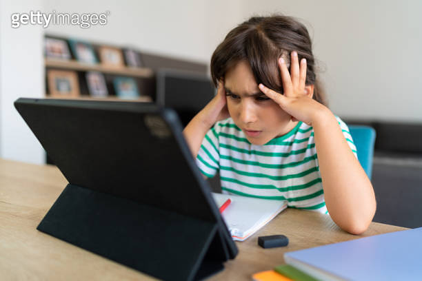Child sitting alone at home and feeling stressed while doing her ...