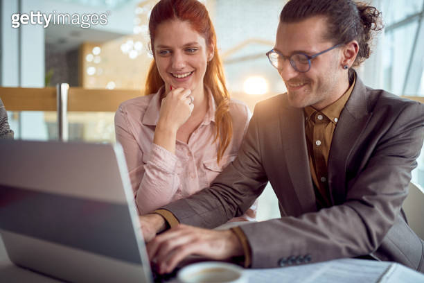 Two young business colleagues at the office enjoying in a laptop ...