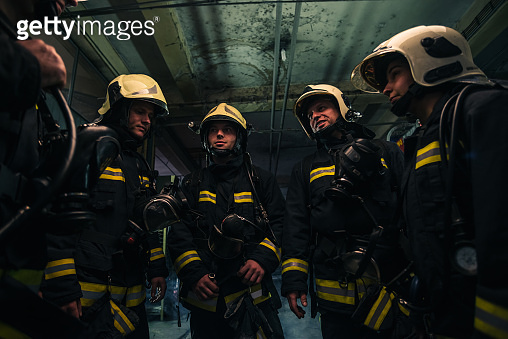 Team of firefighters standing inside ( indoors ) a building next to a ...