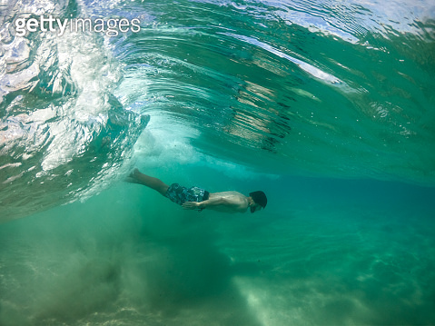 Man diving into a breaking wave at Fernando de Noronha archipelago ...