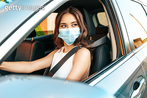 Elegant asian ethnicity woman in a medical face mask driving car ...