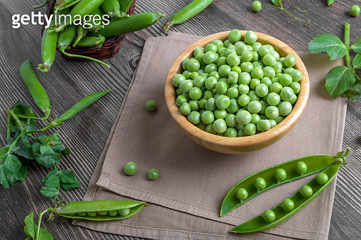 Fresh organic raw green peas in a bowl with peas plants leaves on dark ...