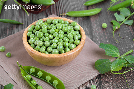 Fresh organic raw green peas in a bowl with peas plants leaves on dark ...