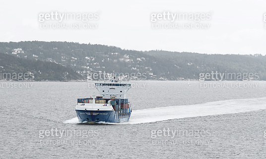Cargo ship or small bulk coaster ship sailing out to sea on a grey ...