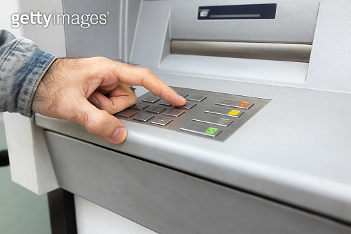 Close-up of hand entering PIN pass code on ATM bank machine keypad ...