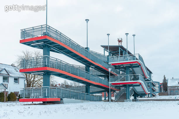 Modern pedestrian metal bridge elevated walkway over railroad in cloudy ...