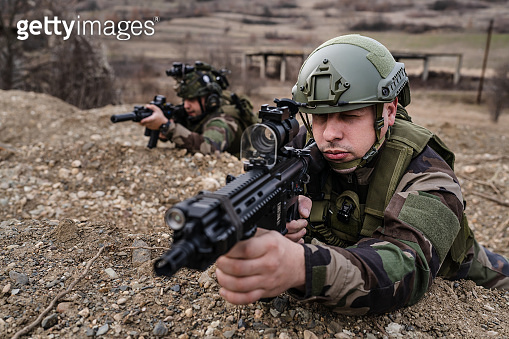 Two men soldiers holding position in the battle war zone aiming rifles ...