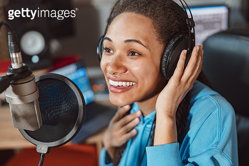 Charming enthusiastic African anchor woman, with headphones talking ...